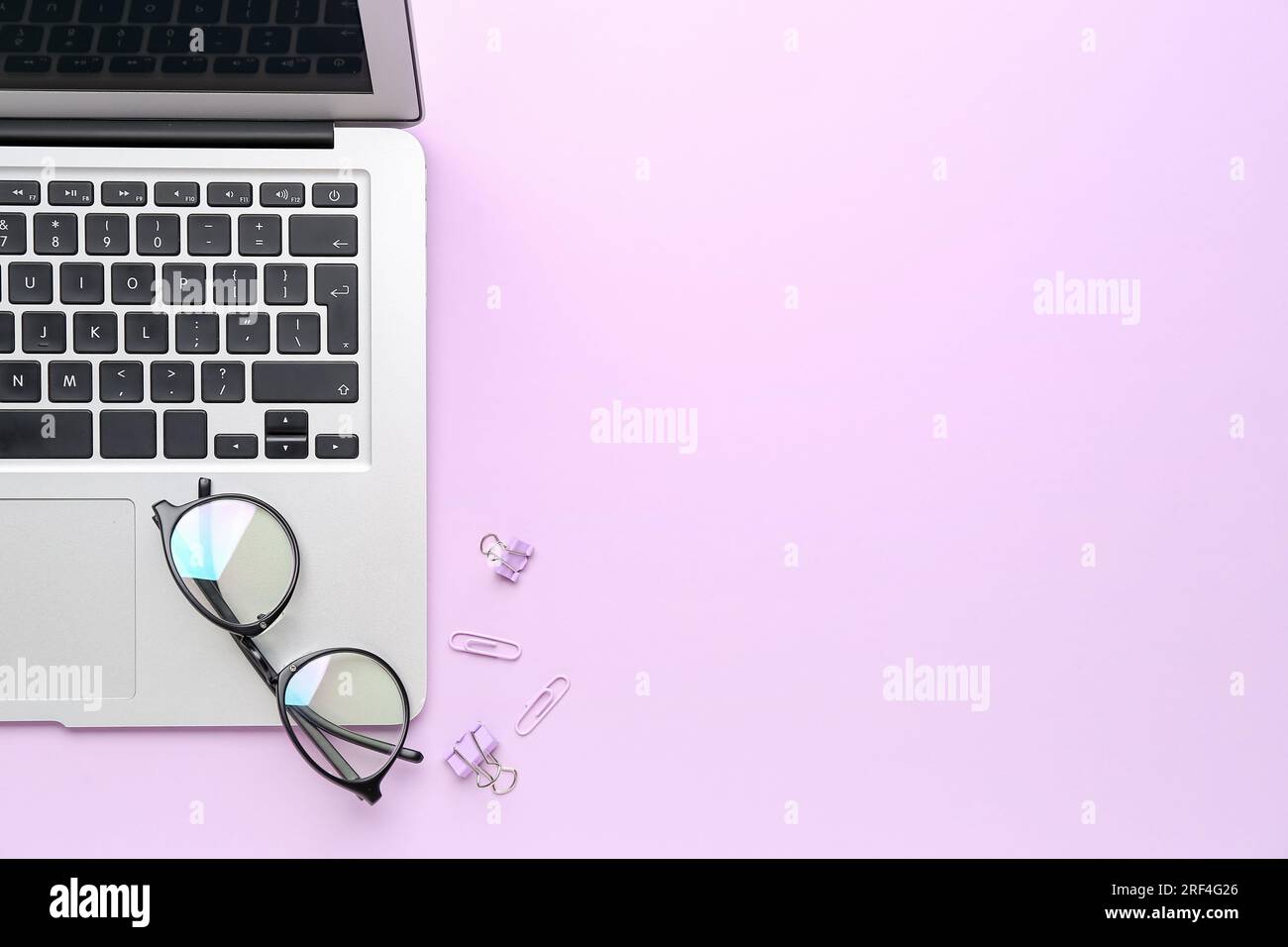 Modern laptop, paper clips and eyeglasses on pink background Stock ...