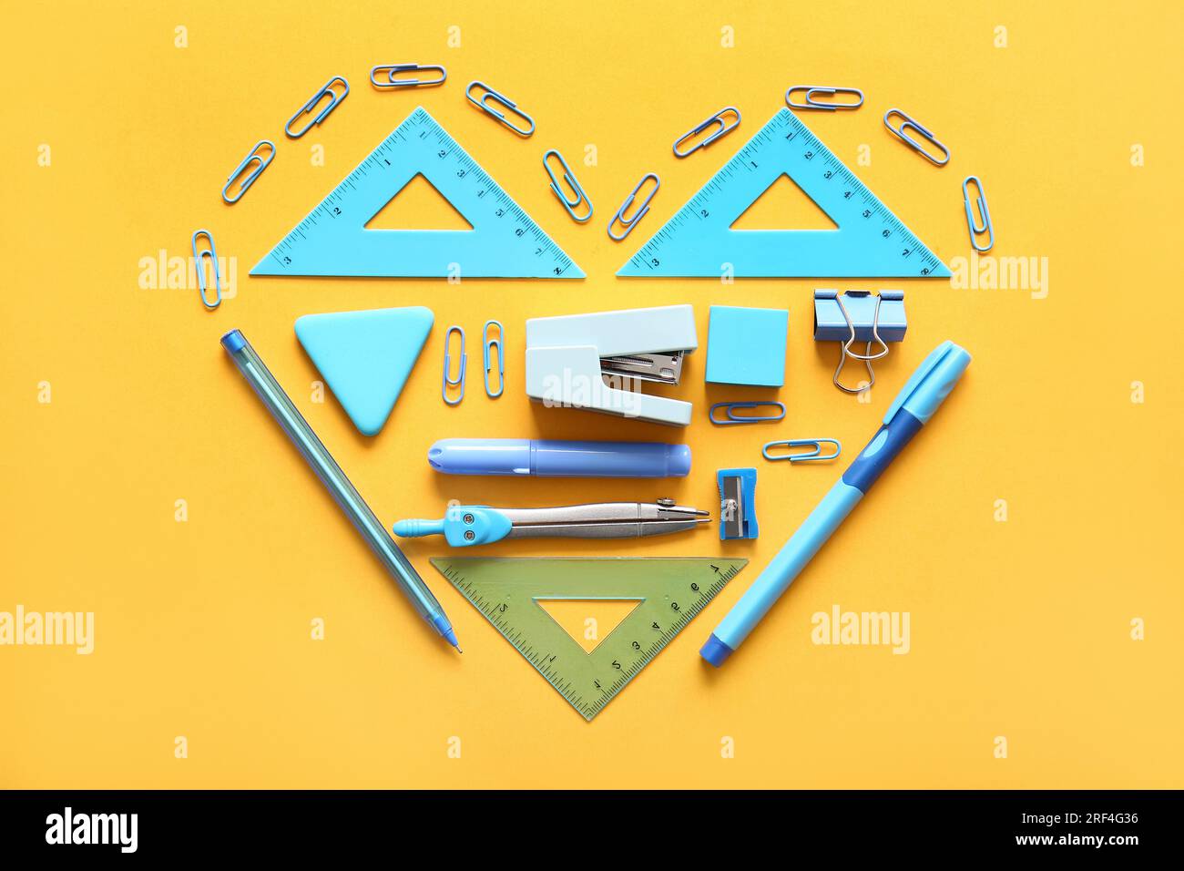 Different school stationery in shape of heart on orange background ...