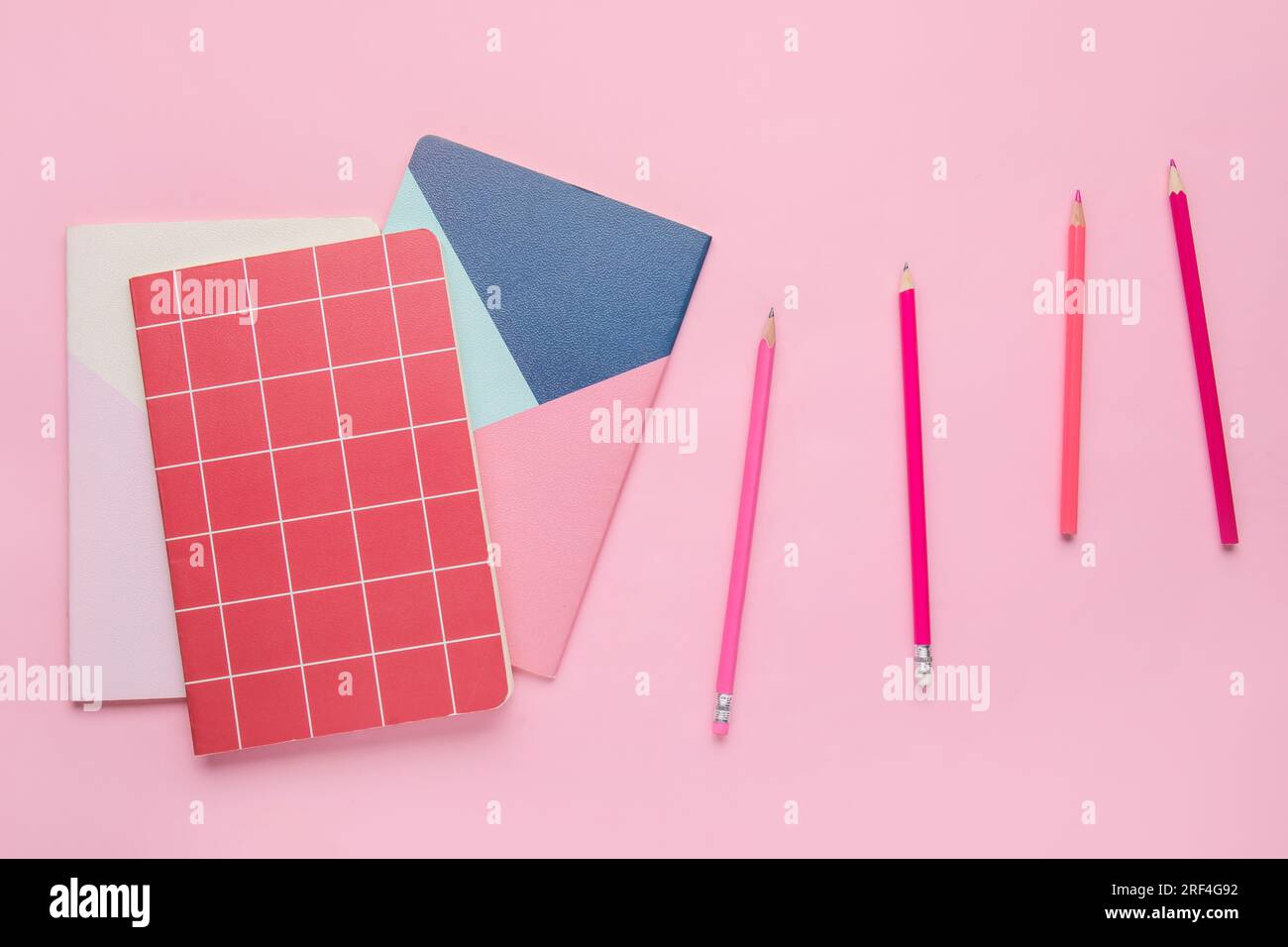 Notebooks and pencils on pink background Stock Photo - Alamy