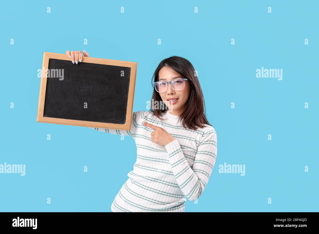 Female Asian teacher pointing at chalkboard on blue background Stock ...