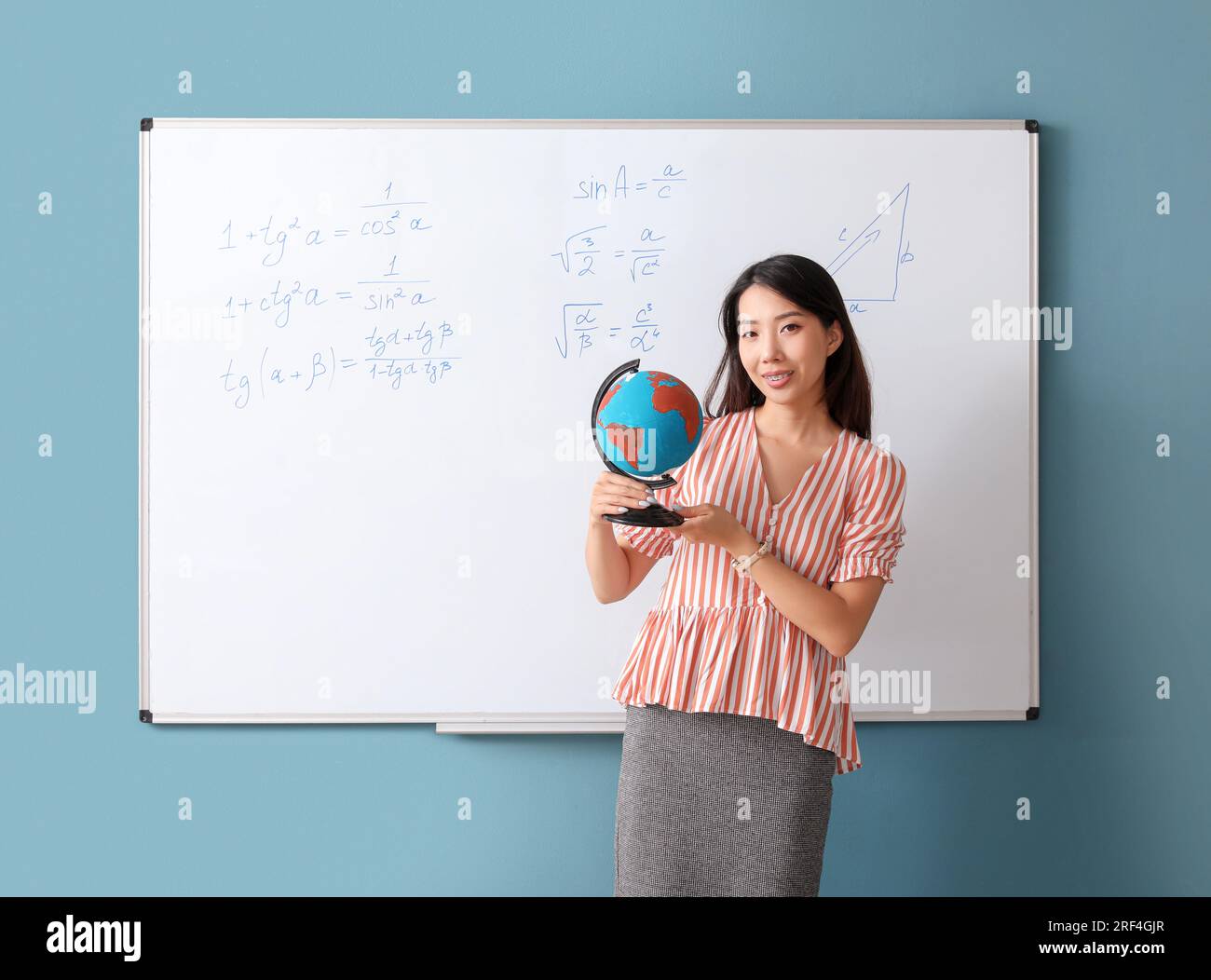 Female Asian teacher with globe near flipboard in classroom Stock Photo ...