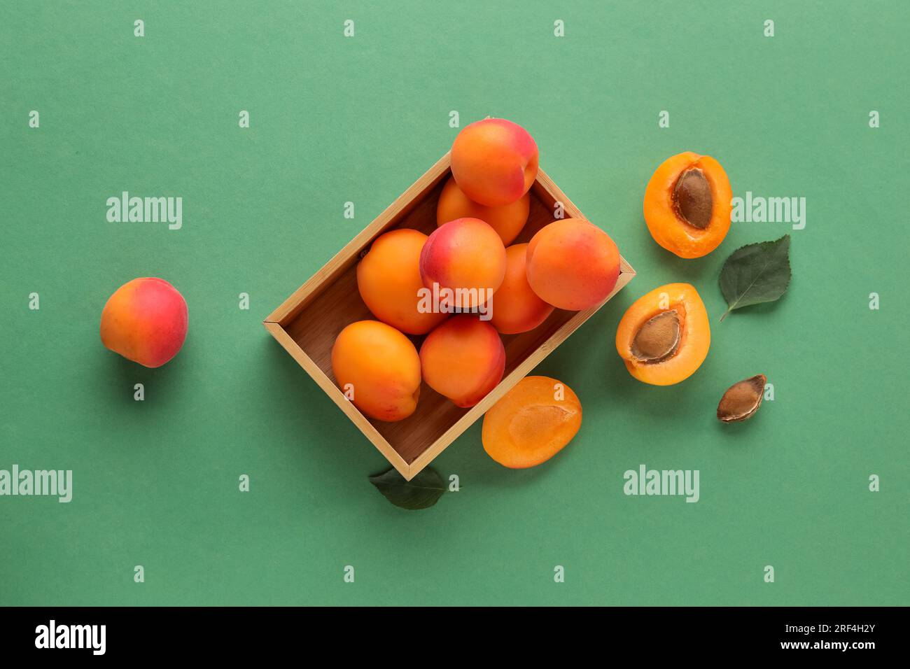 Wooden box with sweet apricots on green background Stock Photo - Alamy
