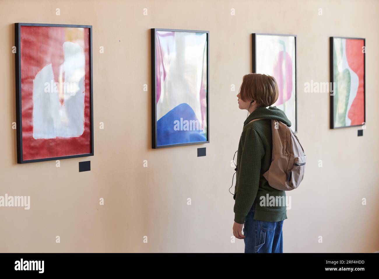 Minimal portrait of teenage boy looking at abstract art on wall in art ...