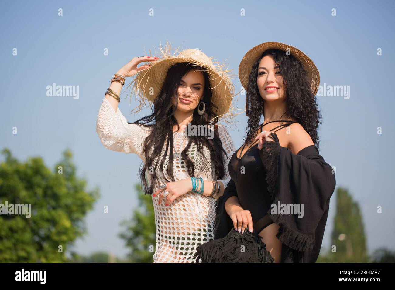 Two female friends in boho style clothes and accessories are relaxing ...