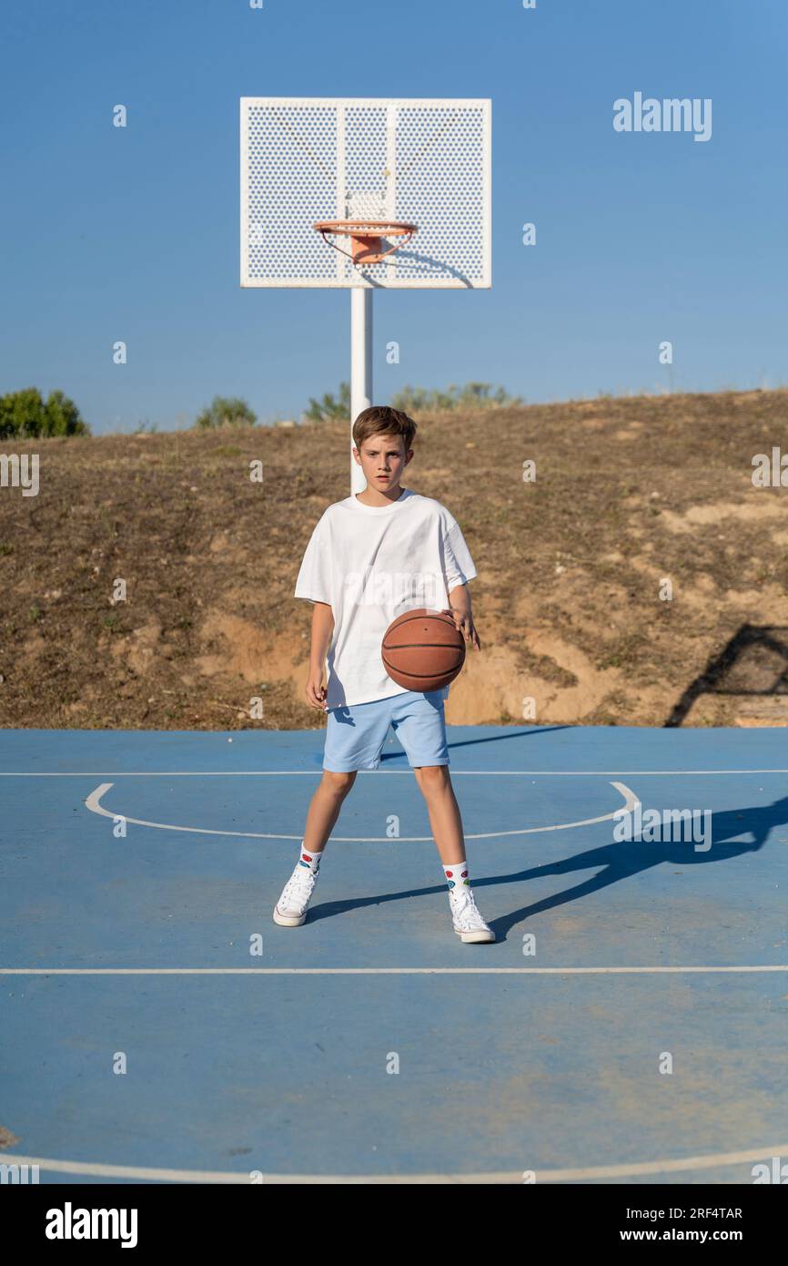 Teenage boy playing basketball on a basketball court in the park ...