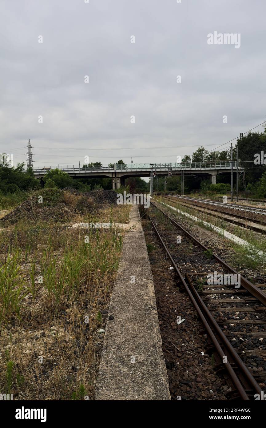 Railroad that passes under a small viaduct on a cloudy day in the ...