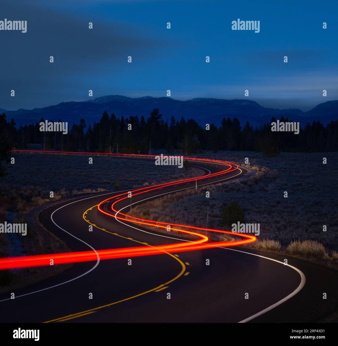 Tail lights illuminate the path of the Grand Teton National Park road ...