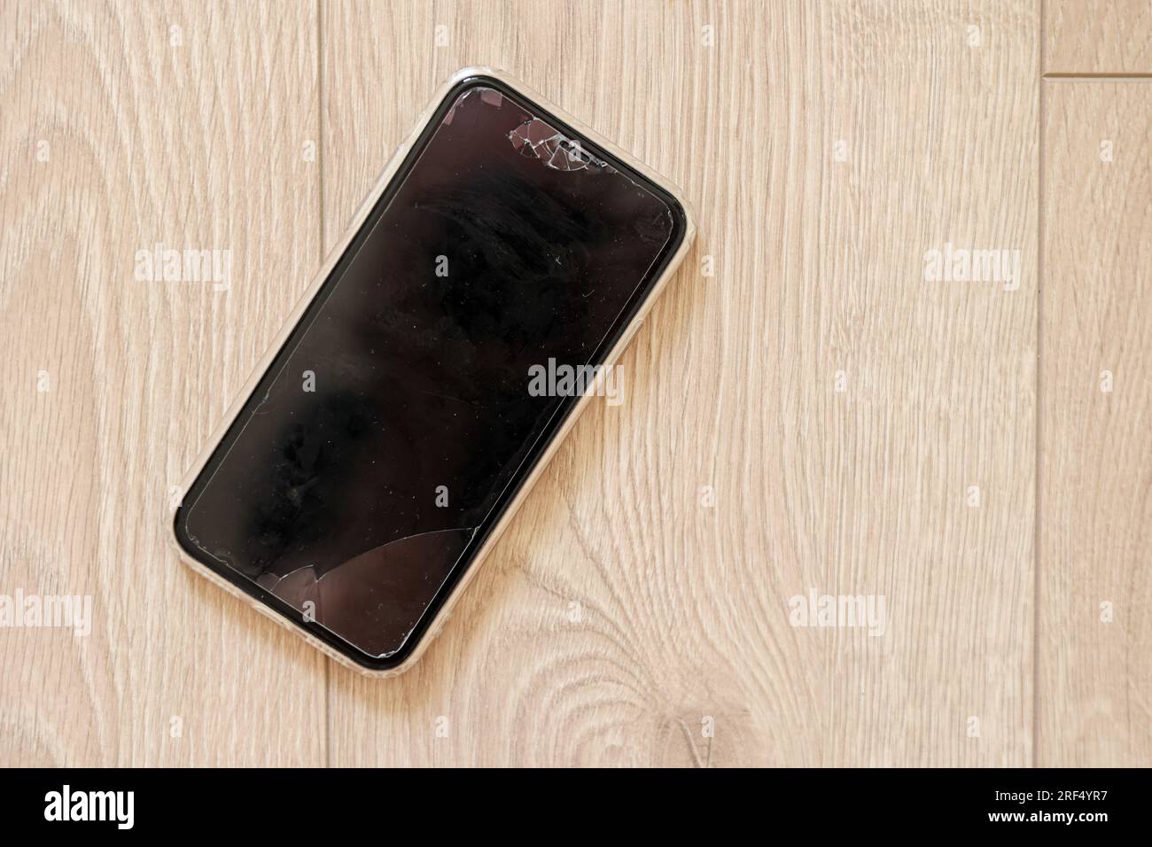 Smartphone with a broken touch screen, glass with cracks on wooden ...