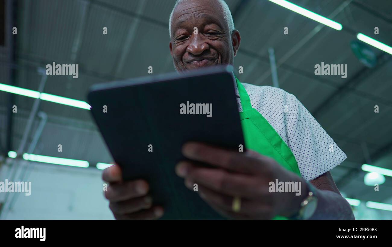 One frustrated black senior staff using tablet device scratching ...