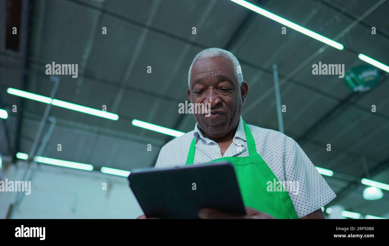 One frustrated black senior staff using tablet device scratching ...