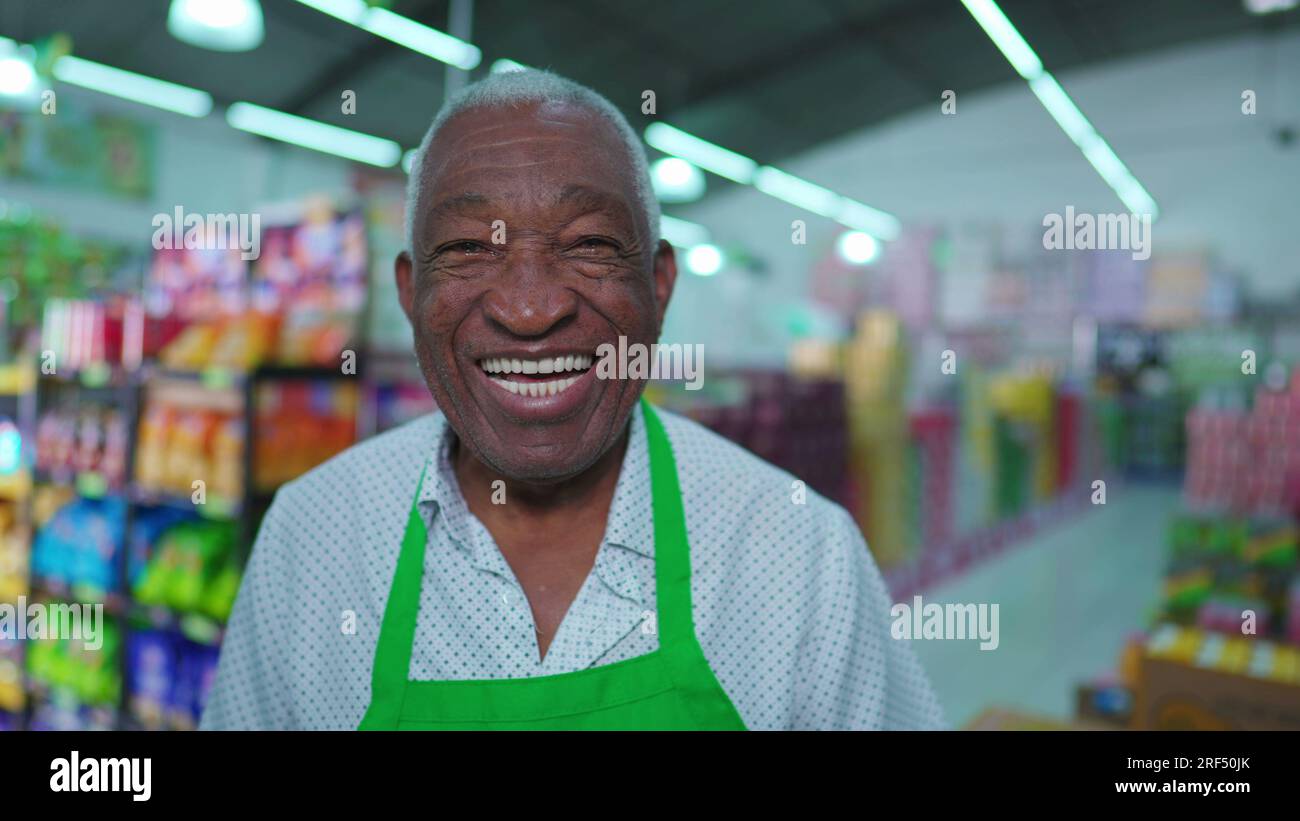 One joyful black senior staff of supermarket smiling at camera standing ...