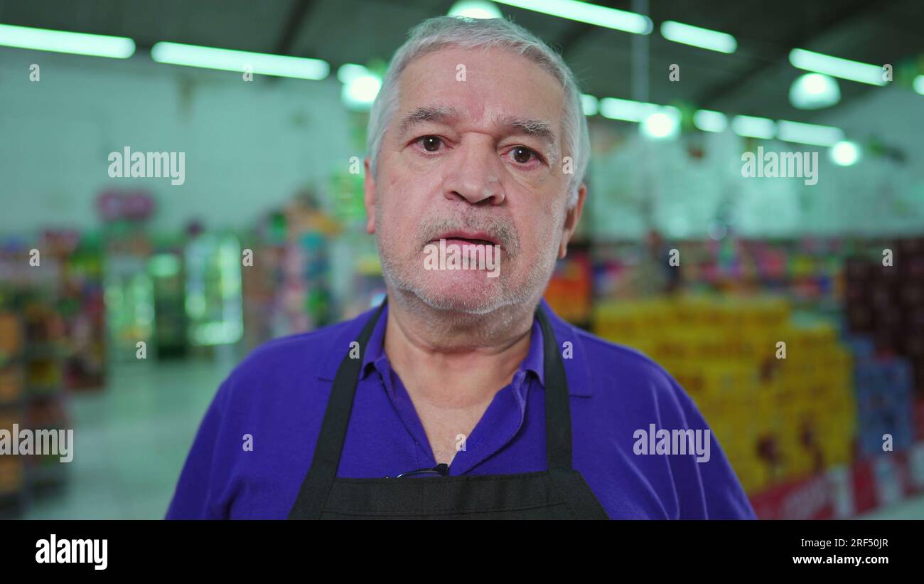 Portrait of a worried elderly manager of supermarket struggling through ...
