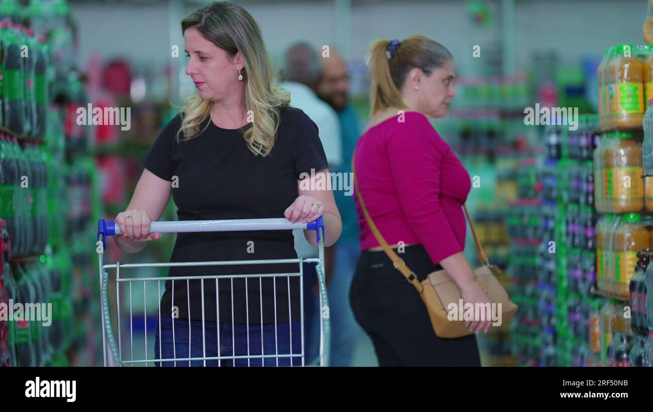 Shoppers at supermarket aisle browsing for products on shelf. Female ...