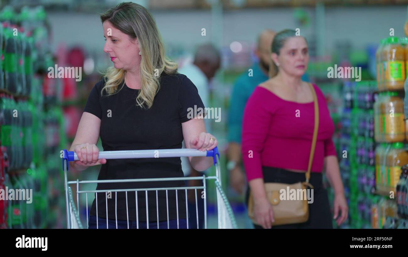 Shoppers at supermarket aisle browsing for products on shelf. Female ...