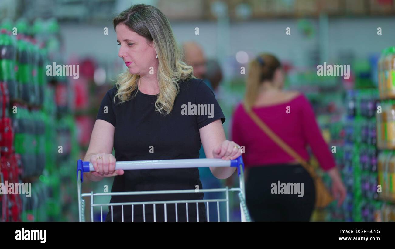 Shoppers at supermarket aisle browsing for products on shelf. Female ...