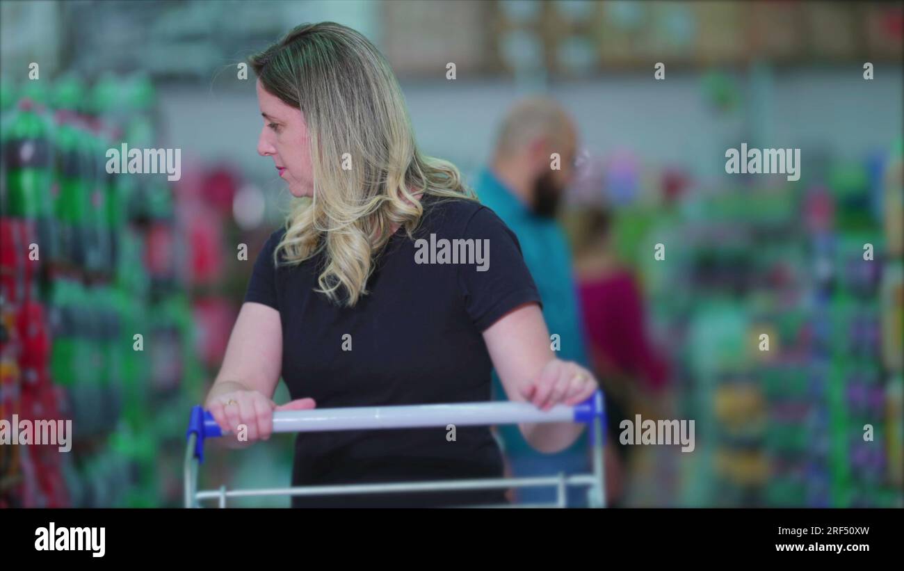Female Consumer with Cart Navigating Supermarket Shelves, Shoppers in ...