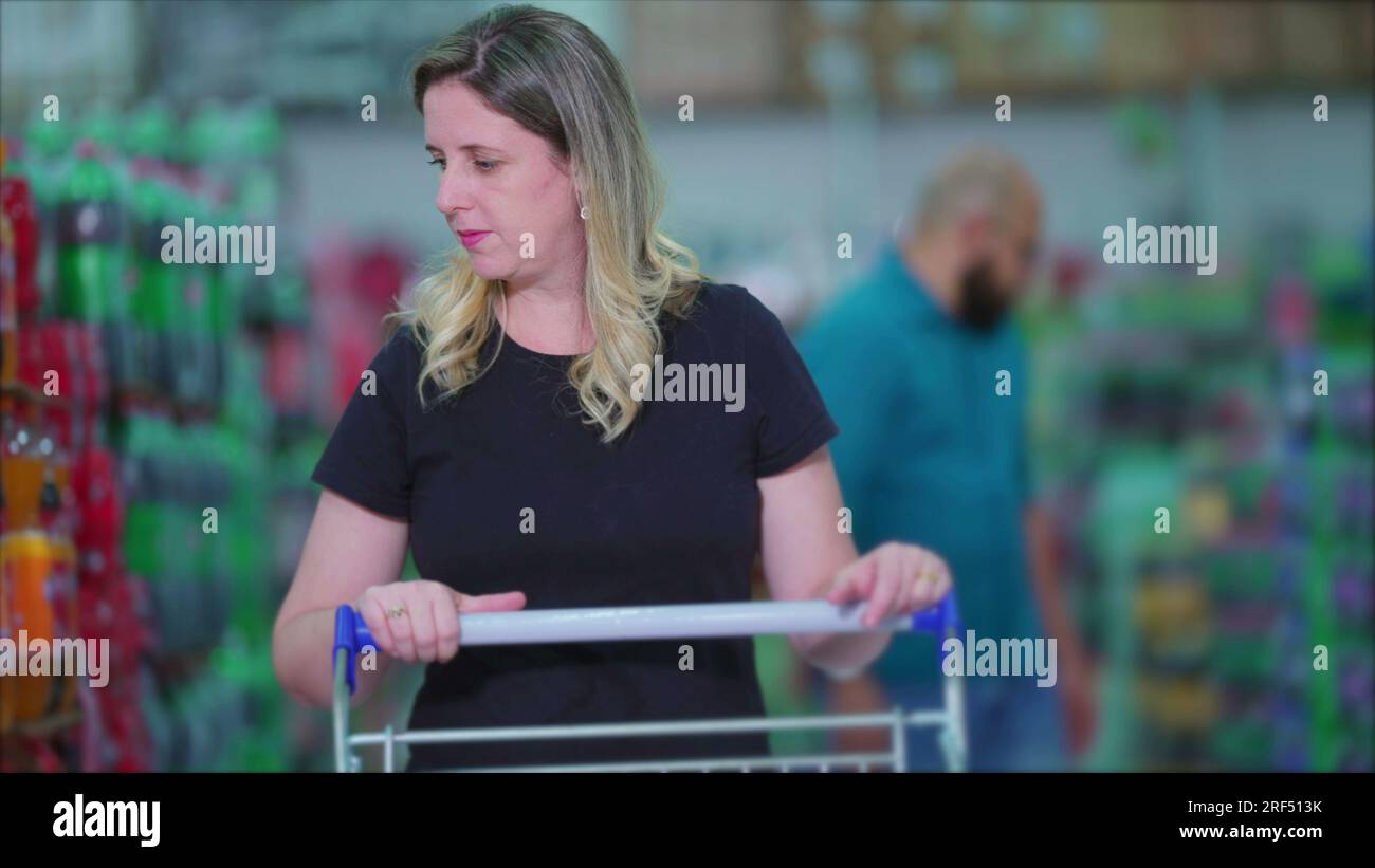 Female Consumer with Cart Navigating Supermarket Shelves, Shoppers in ...