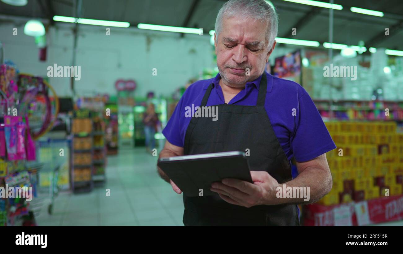 Frustrated Business owner of Supermarket holding tablet inspecting ...