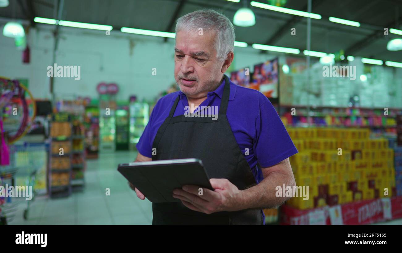 Frustrated Business owner of Supermarket holding tablet inspecting ...
