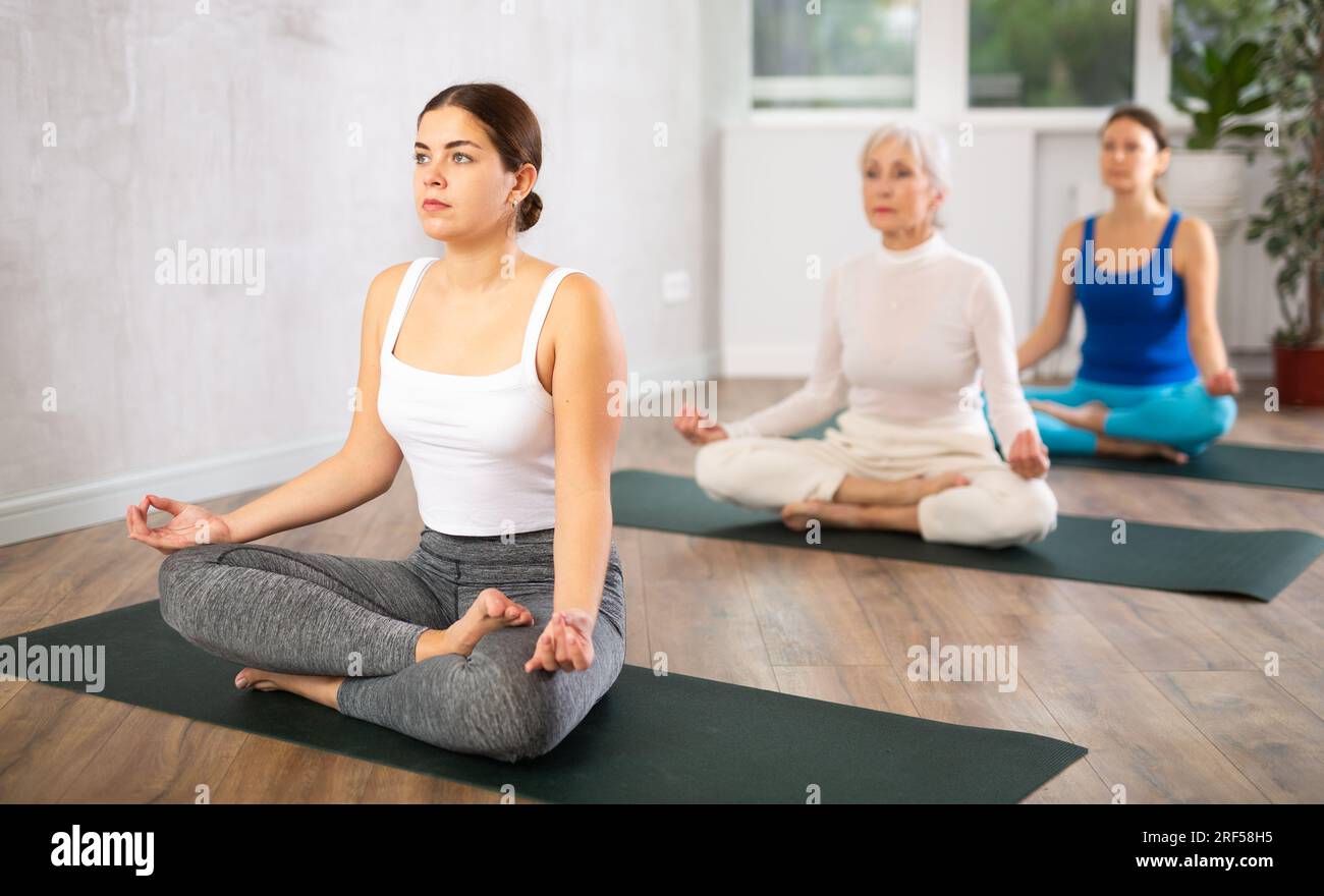 Sport women perform the exercise while sitting in the lotus position ...