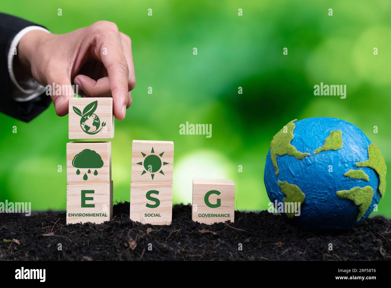 Businessman holding paper earth planet with ESG symbol wooden cube ...