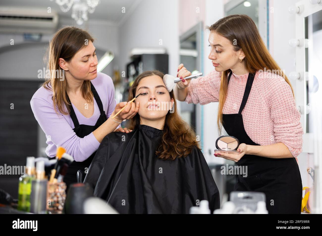 Two female makeup artists working with young girl client Stock Photo ...