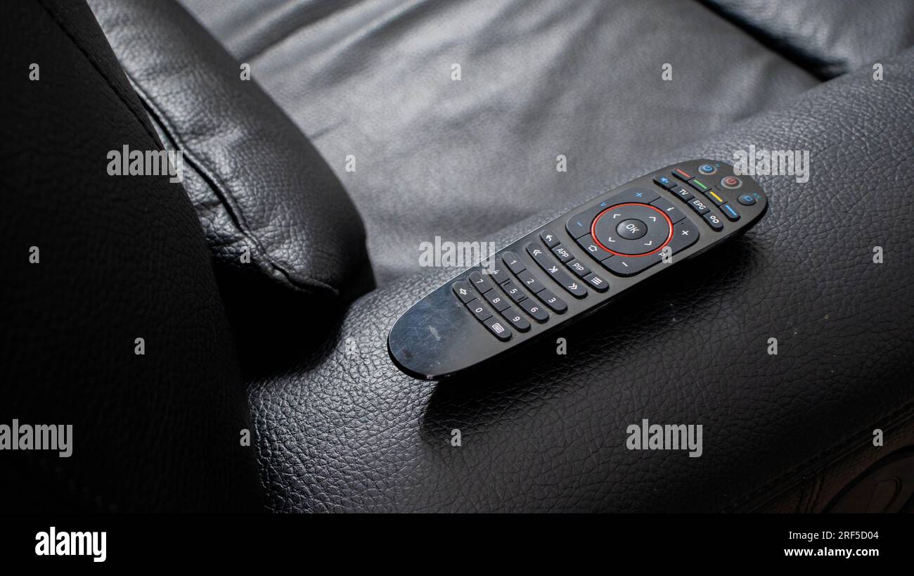 The Television Remote sits on a leather recliner sofa Stock Photo - Alamy
