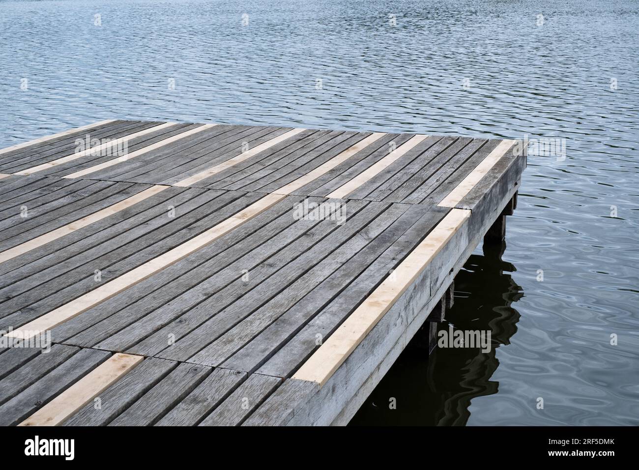 Aged and renovated wooden pier dock on lake. Surface of a wooden pier ...