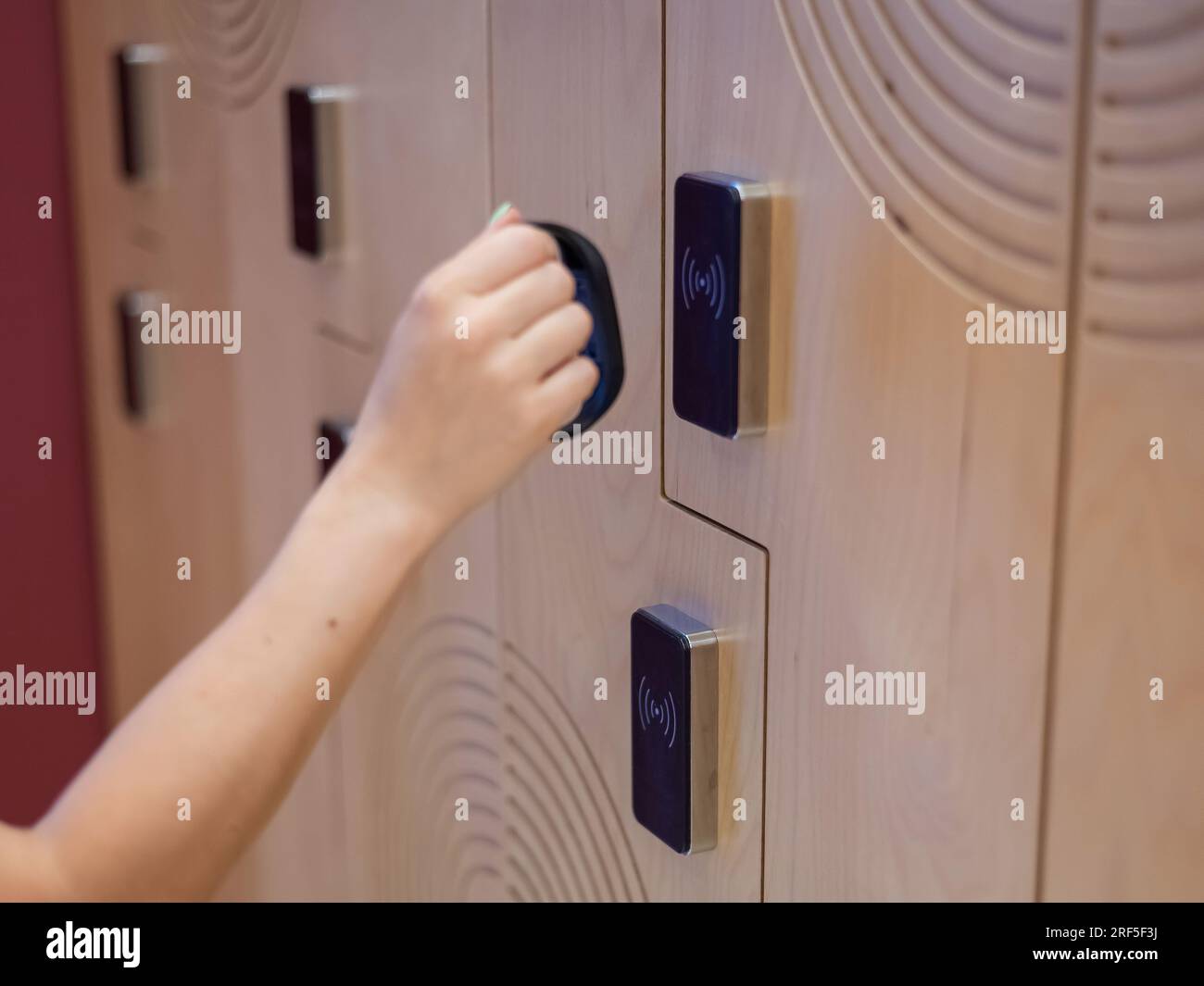 A woman opens the electronic lock of a cubicle in a locker room with a ...