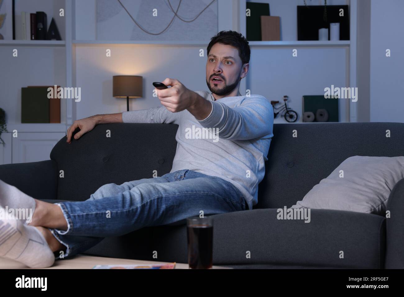 Man changing TV channels with remote control on sofa at home Stock ...