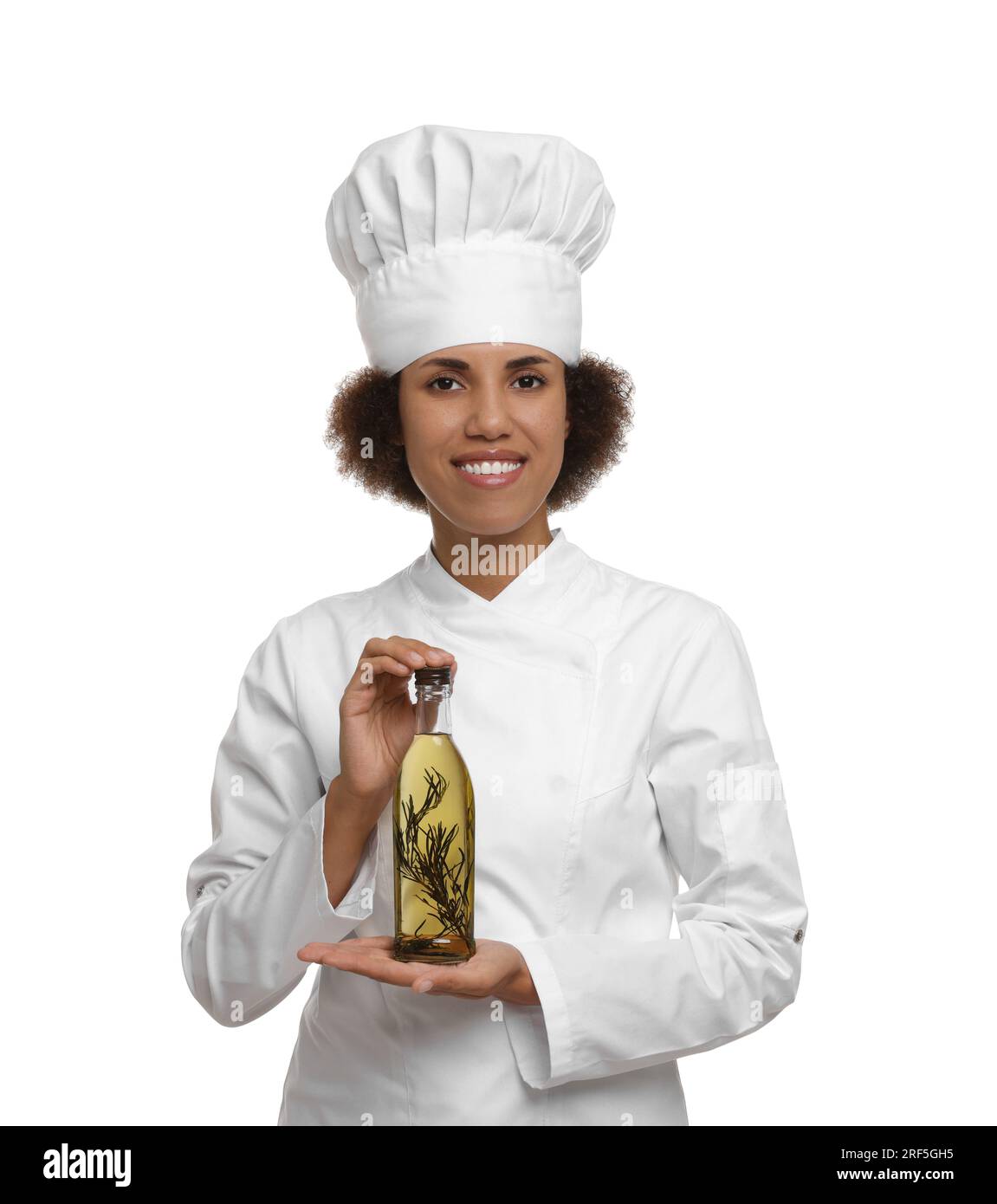 Happy female chef in uniform holding bottle of cooking oil on white ...
