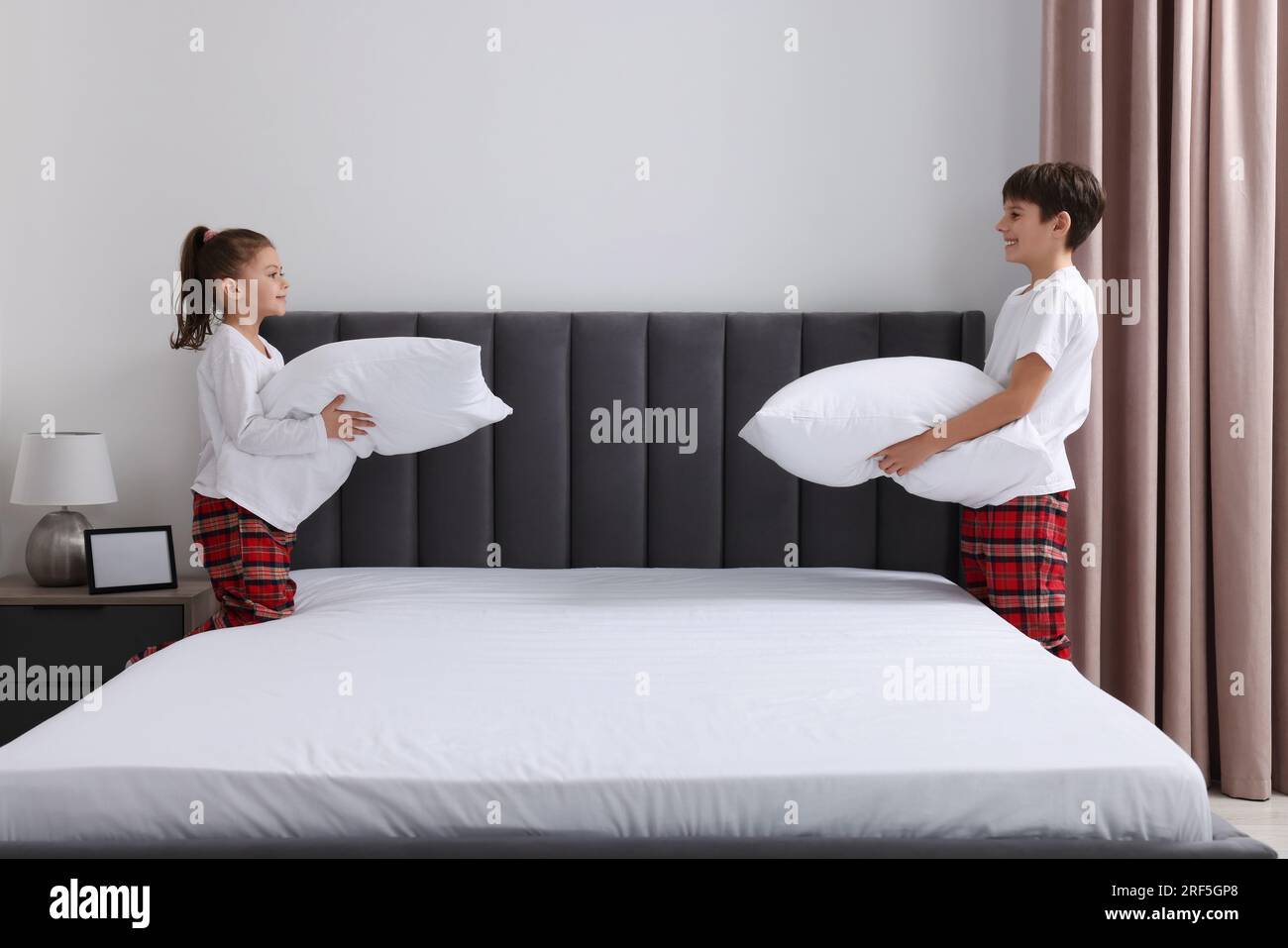 Brother and sister changing bed linens together in bedroom Stock Photo ...