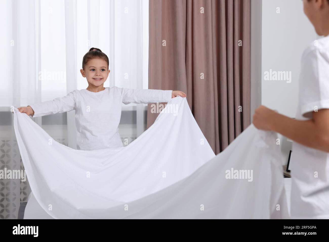 Brother and sister changing bed linens together in bedroom Stock Photo ...