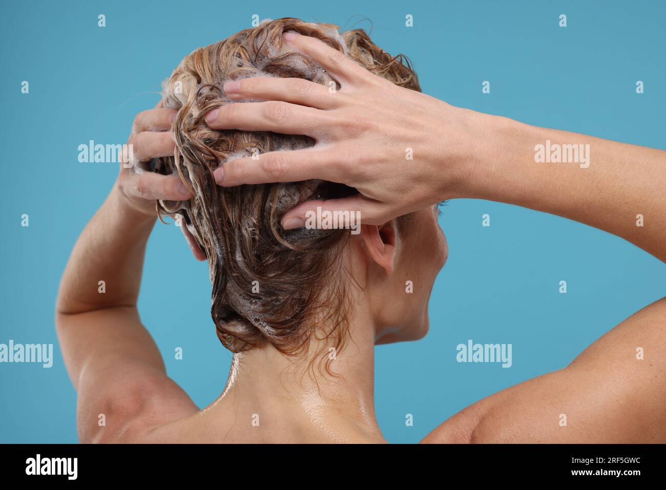 Woman washing hair on light blue background Stock Photo - Alamy