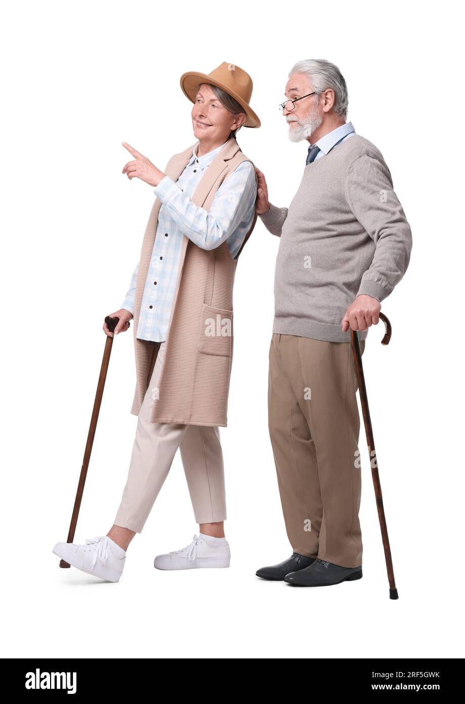 Senior man and woman with walking canes looking at something on white ...