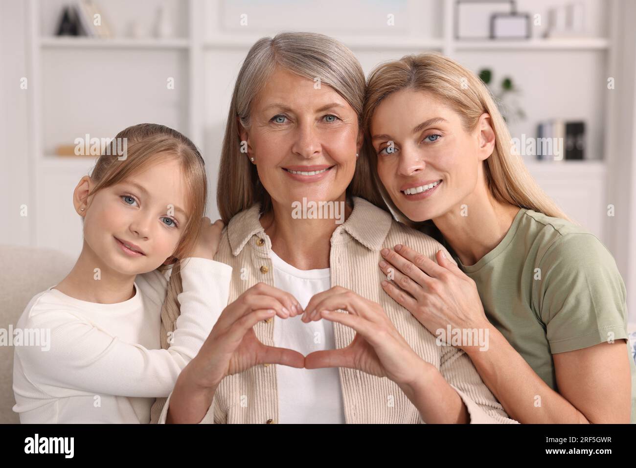 Three generations. Happy grandmother showing heart gesture with her ...