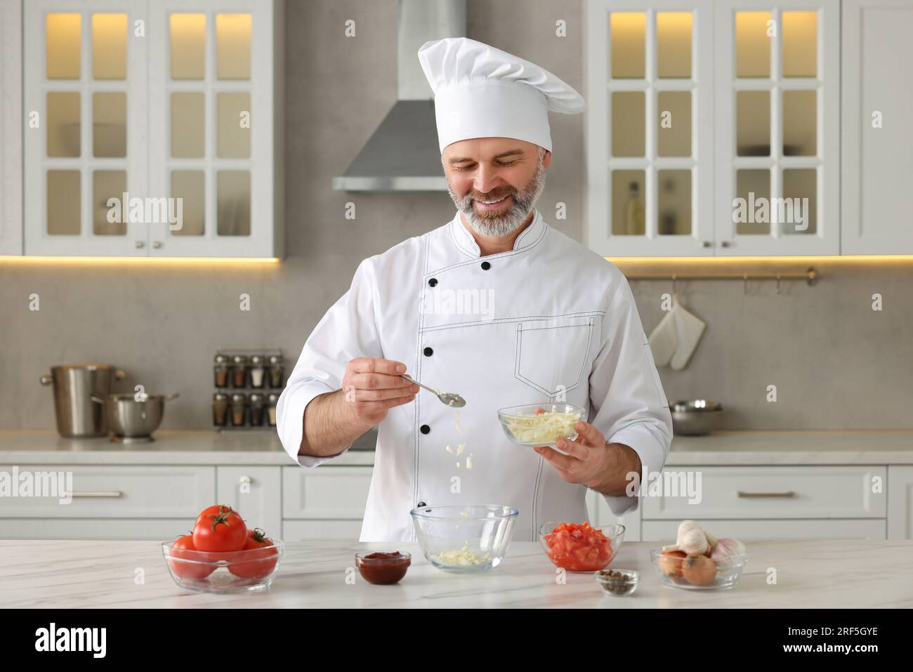 Professional chef making delicious tomato sauce at white marble table ...