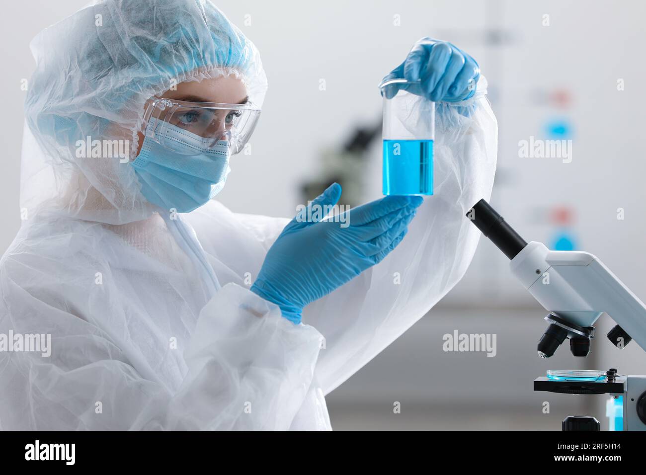 Young scientist holding beaker with sample in laboratory Stock Photo ...