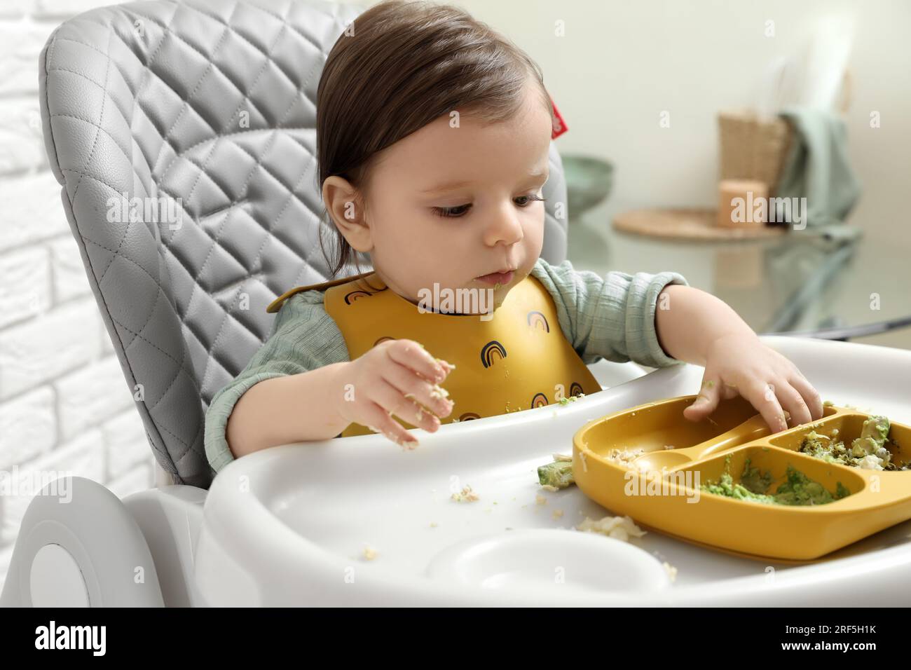 Cute little baby eating healthy food in high chair indoors Stock Photo ...