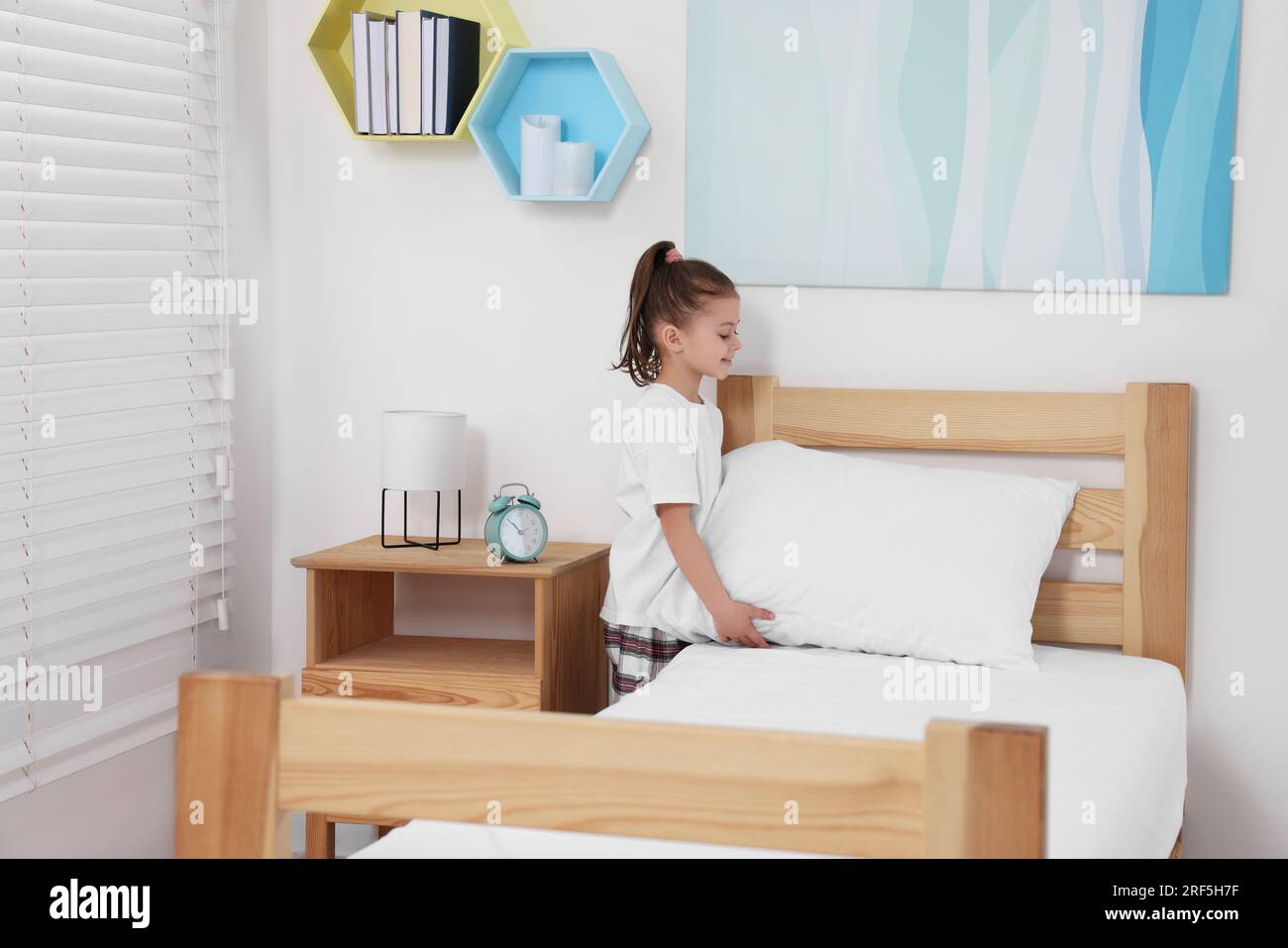 Cute girl changing bed linens in children room Stock Photo - Alamy