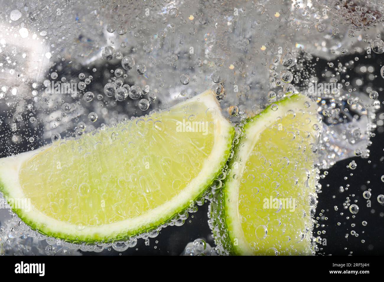 Juicy lime slices and ice cubes in soda water against black background, closeup Stock Photo - Alamy