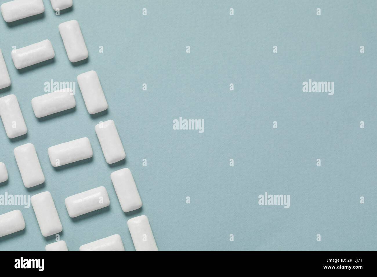 Tasty white chewing gums on light blue background, flat lay. Space for ...