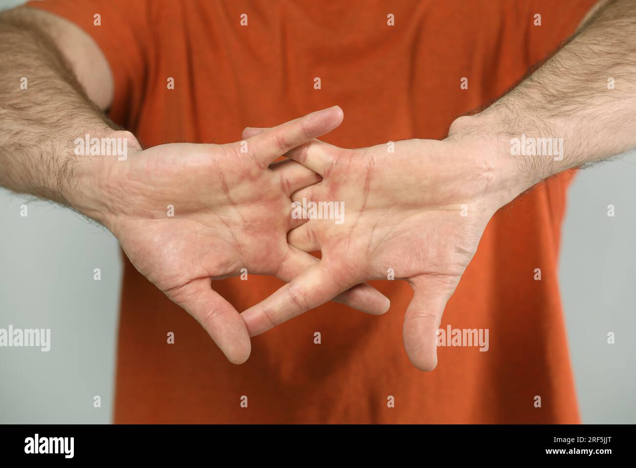 Man cracking his knuckles on light grey background, closeup. Bad habit ...