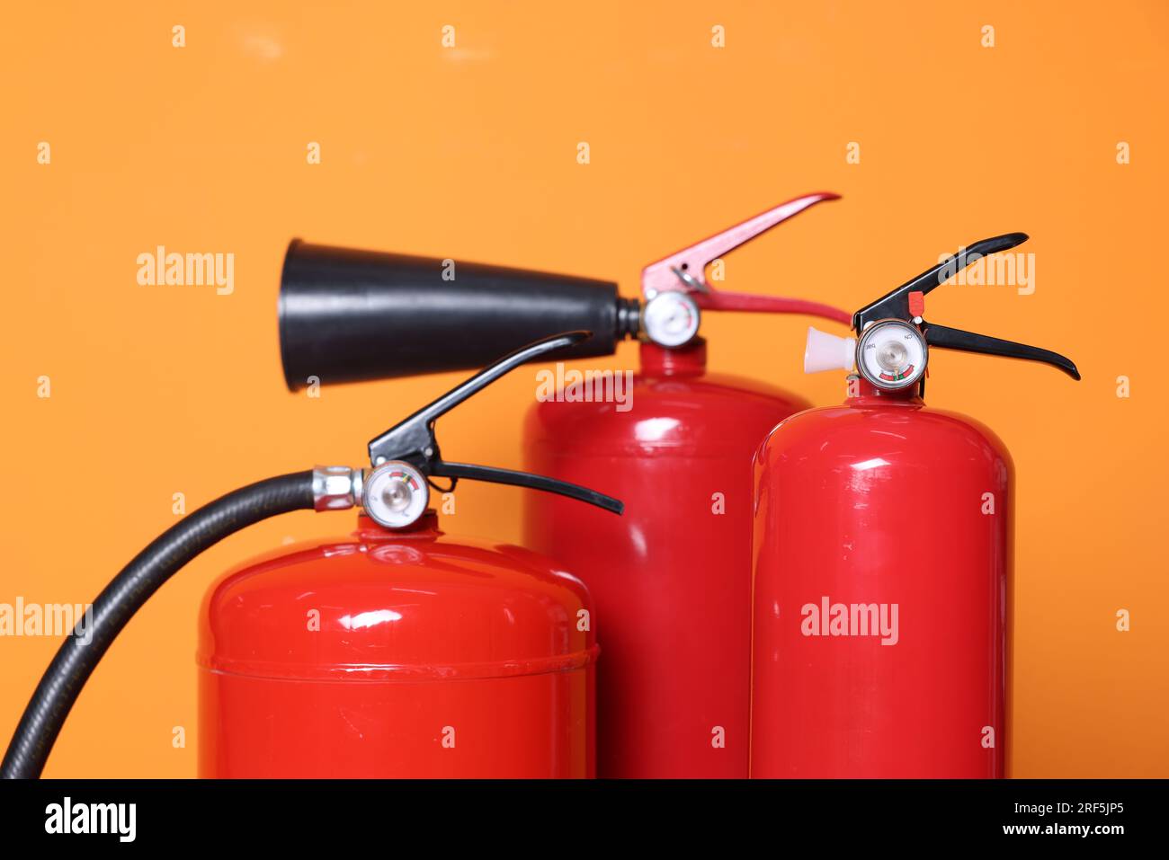 Three red fire extinguishers on orange background, closeup Stock Photo ...