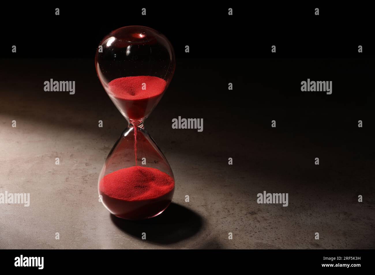 Hourglass with red flowing sand on grey table. Space for text Stock ...