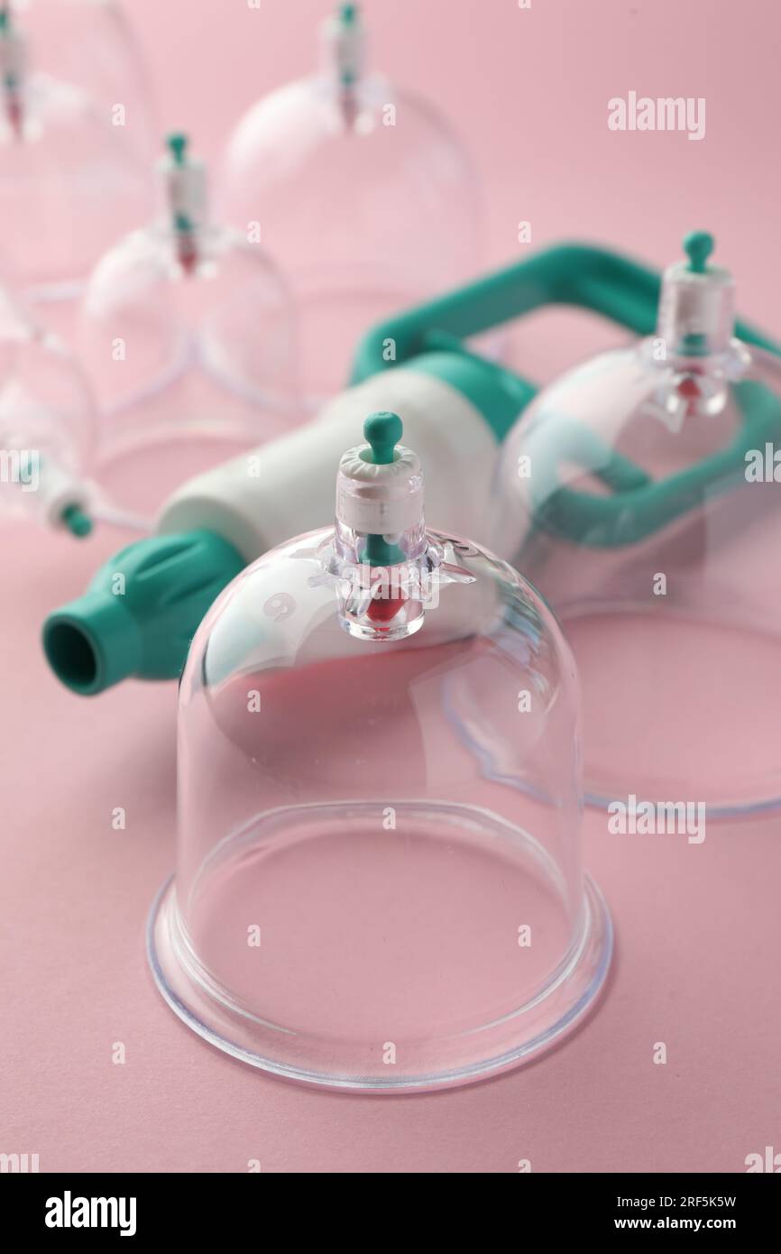 Plastic cups and hand pump on pink background, closeup. Cupping therapy ...
