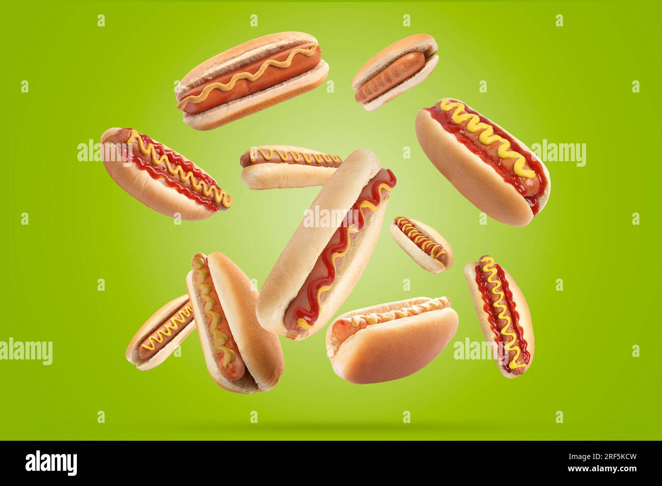 Many tasty hot dogs falling on green background Stock Photo - Alamy