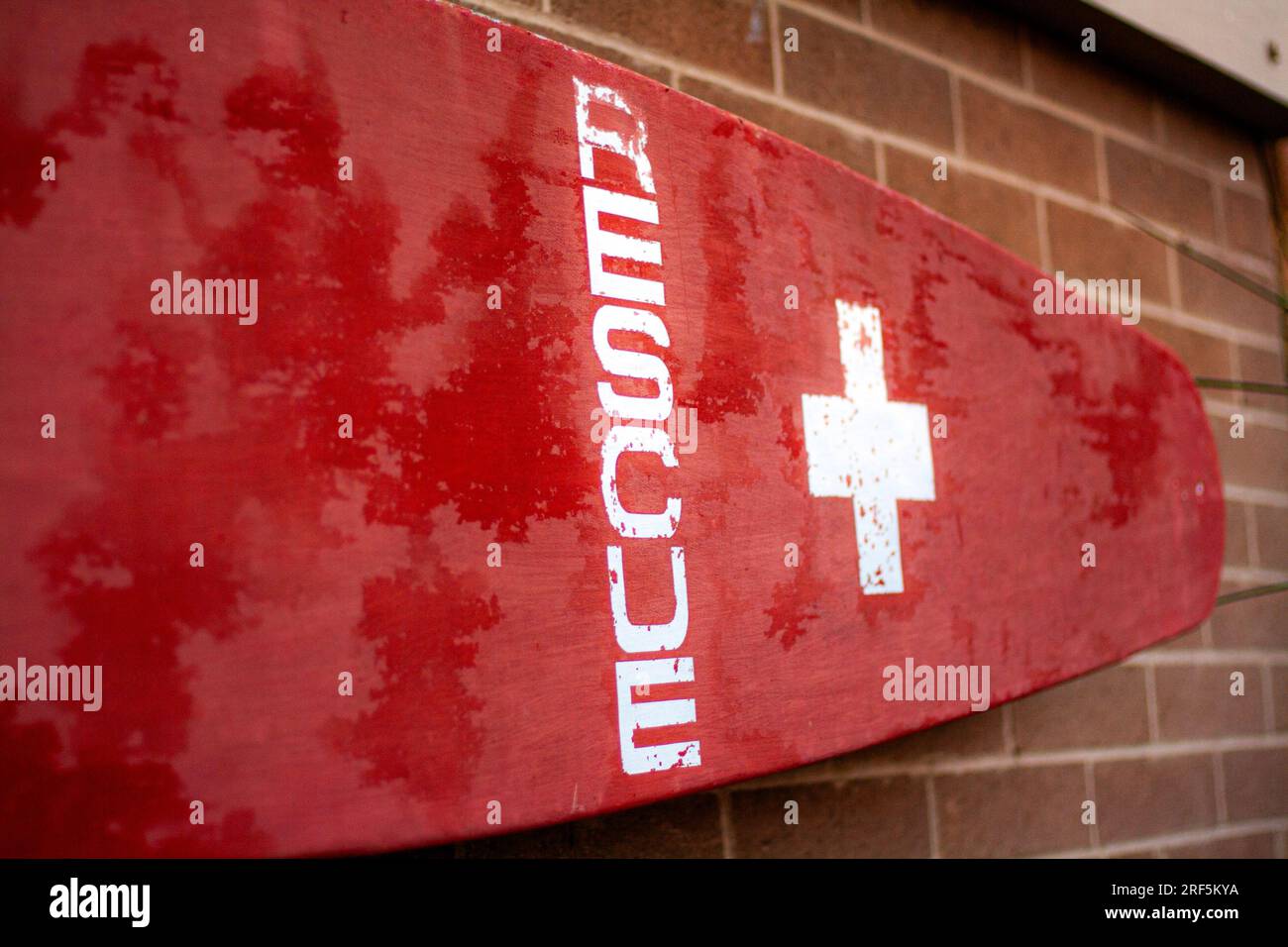 A red lifeguard surfboard with Rescue and a white cross Stock Photo - Alamy