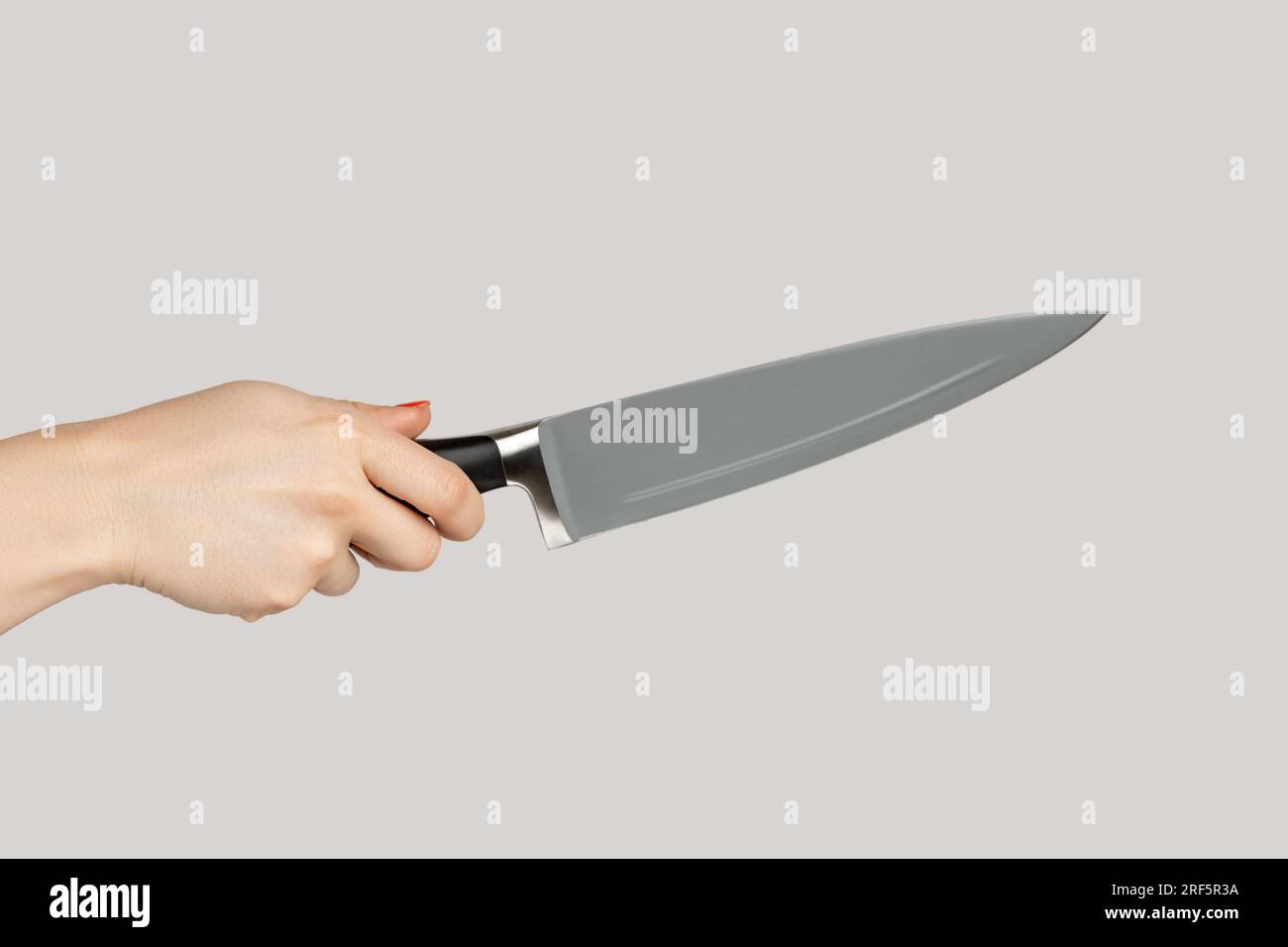 Closeup of woman hand holding huge sharp kitchen knife. Indoor studio ...