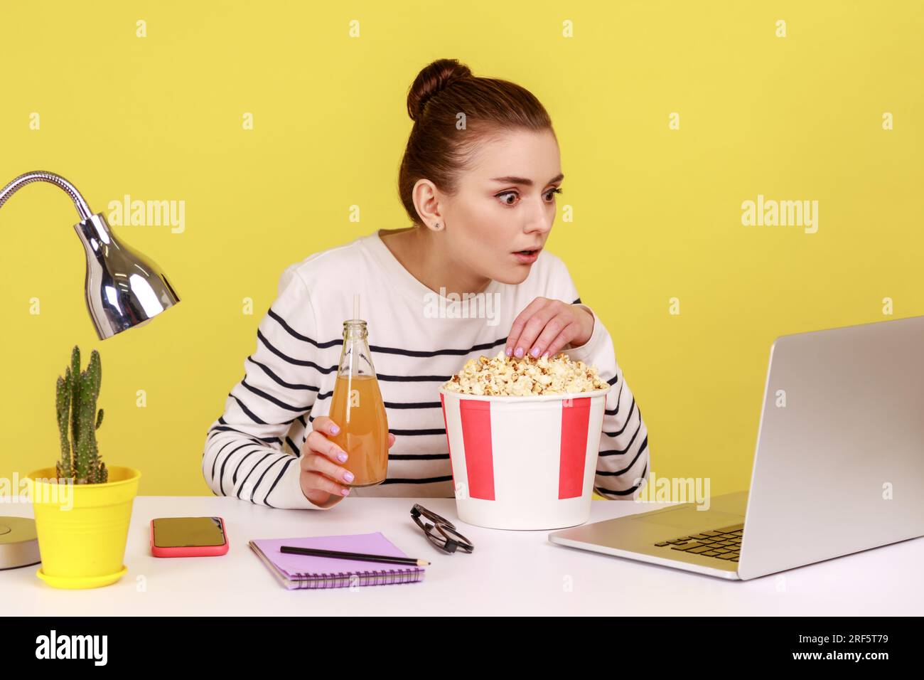 Concentrated woman sitting on workplace and watching interesting movie ...